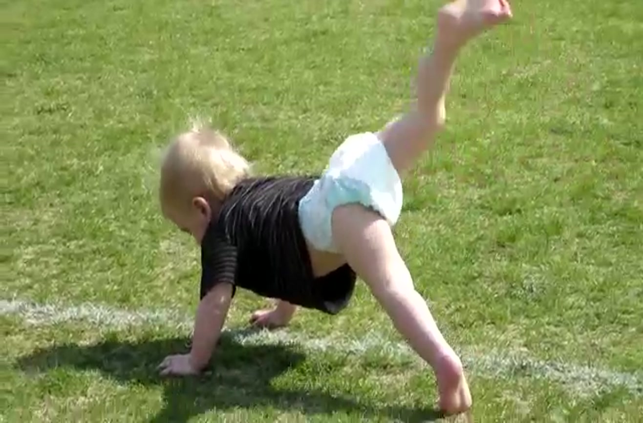 A baby gives some stretching lessons on the sidelines.