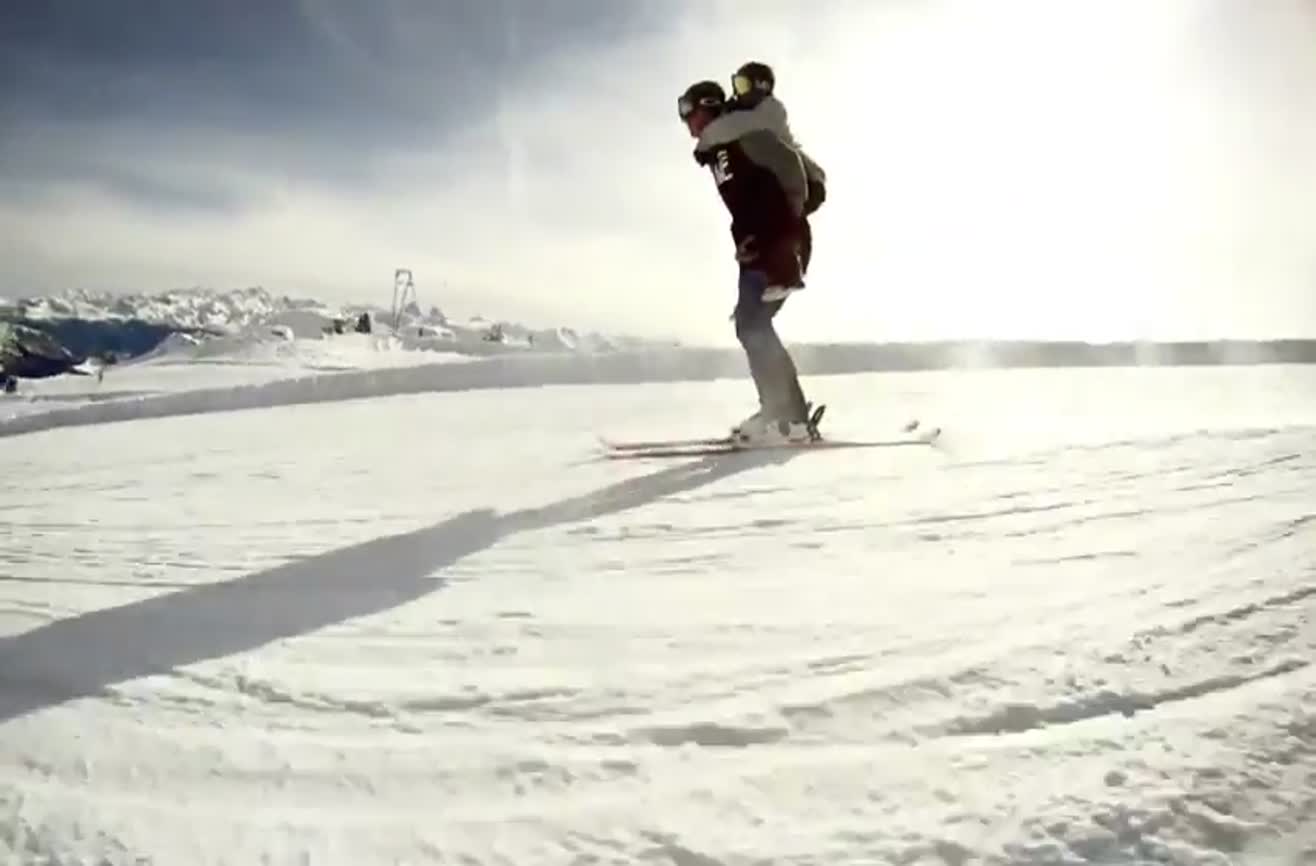 Skier rides piggyback off a jump.