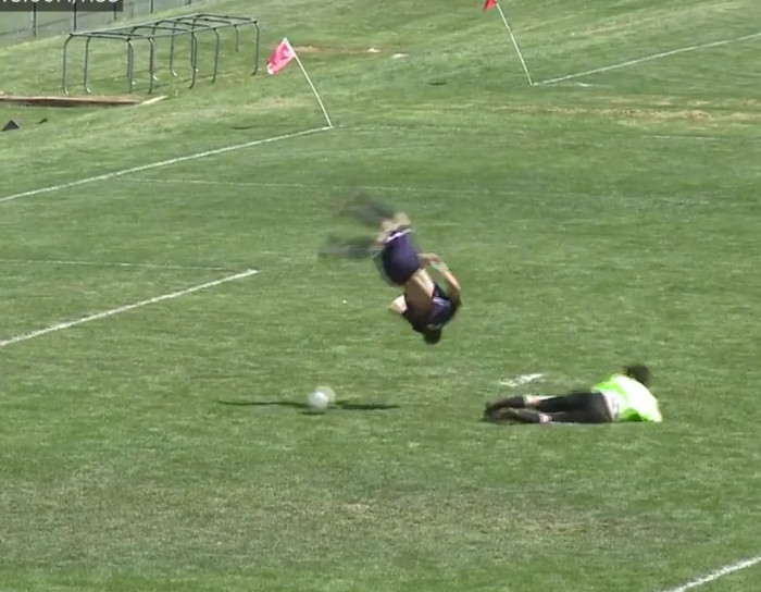 High school soccer player flips over goalie to score.