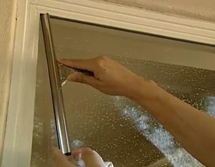 Professional window washer demonstrates how to correctly wash a window.