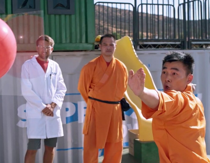 A Shaolin monk throwing a needle through a pane of glass in slow motion.