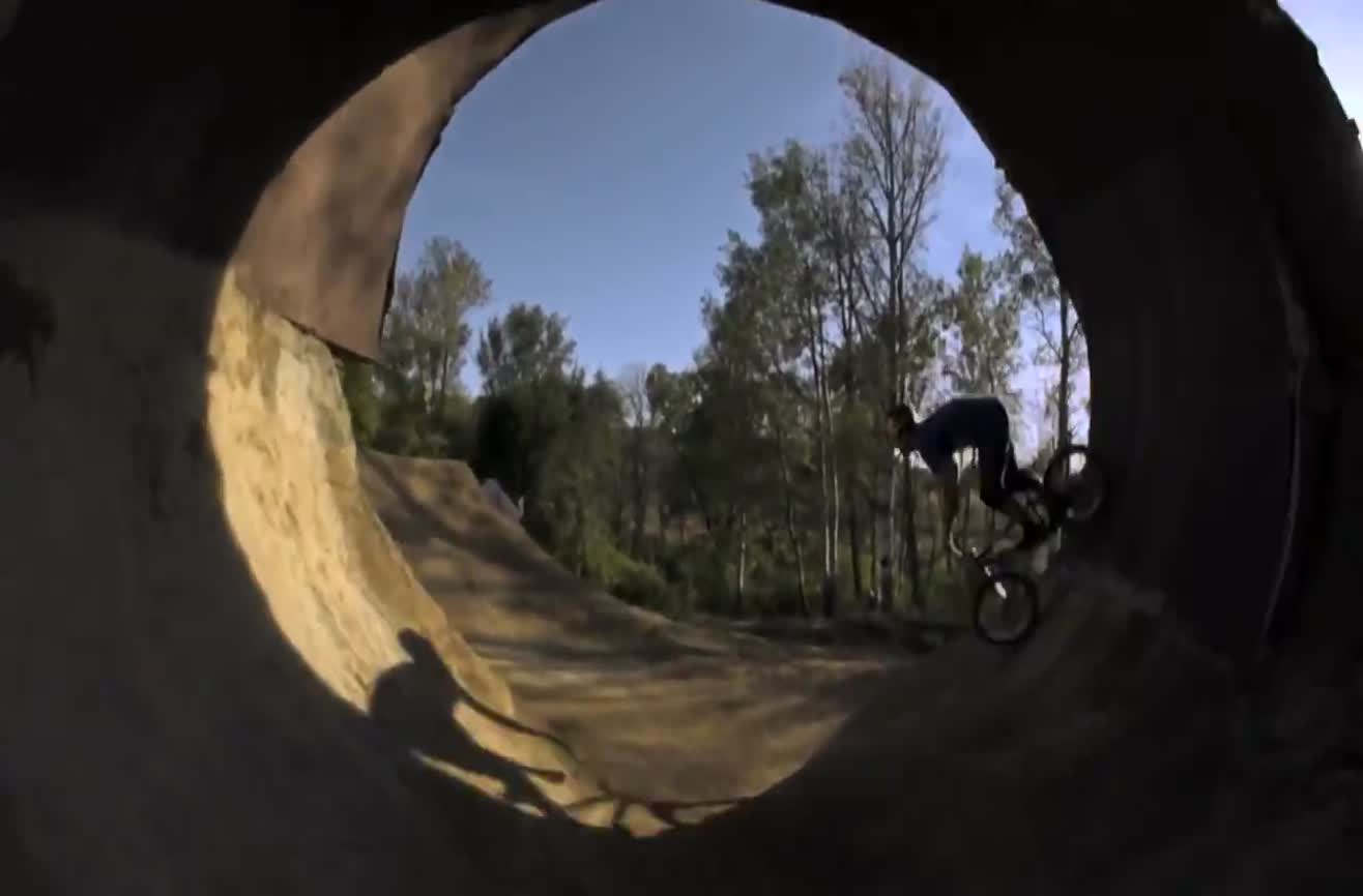 BMX rider completes loop made out of wood and dirt.