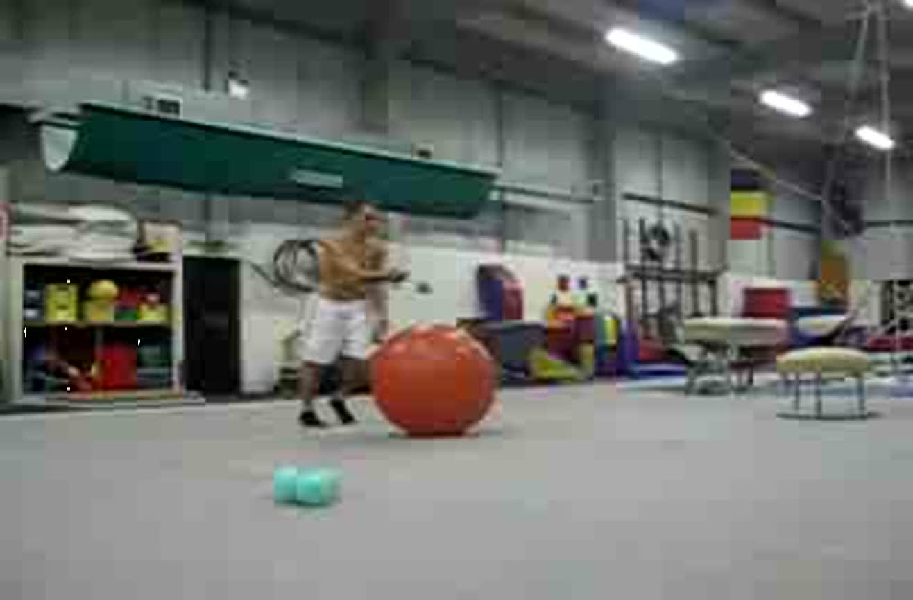 Man performs acrobatic stunt on exercise ball.