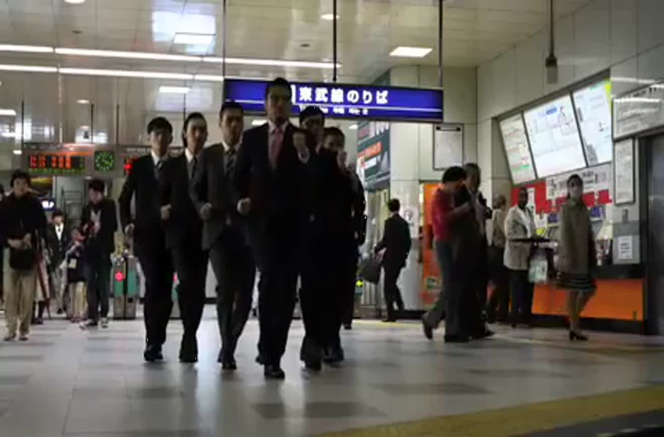 Japanese men running in synchronized slow motion.