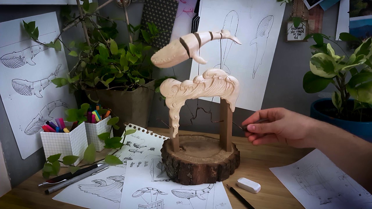 Kinetic wooden sculpture of white humpback whale swimming above the waves