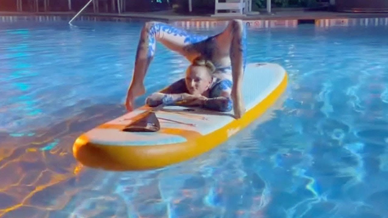 Contortionist on floating surfboard.