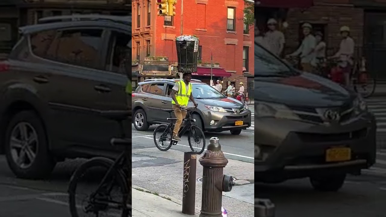 Man does bike tricks while balancing trash can on his head.